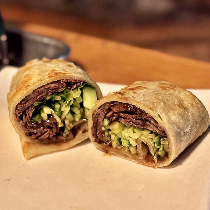 The beef roll at Pine & Crane is architecture as much as food—layers of tender meat, crisp vegetables, and herbs wrapped in a flaky pancake that shatters just so.