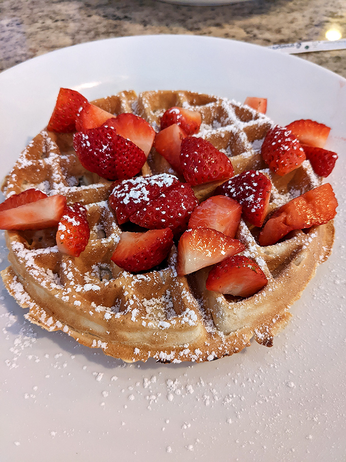 A waffle topped with fresh strawberries and powdered sugar&mdash;because sometimes breakfast should feel like dessert and no one should make you feel guilty about it. 