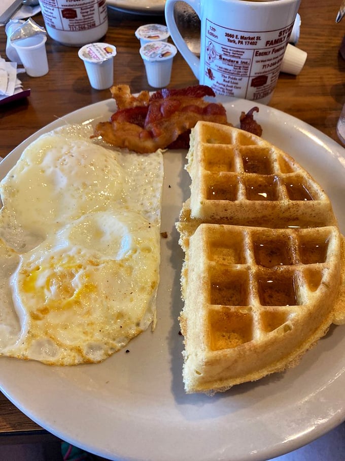 The breakfast trinity: perfectly cooked eggs, bacon with just the right crisp, and a waffle that makes pancakes jealous of its perfect grid pattern.