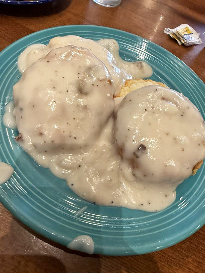 Biscuits drowning in creamy gravy represent comfort food at its finest, like a warm hug from your grandmother's kitchen on a plate.