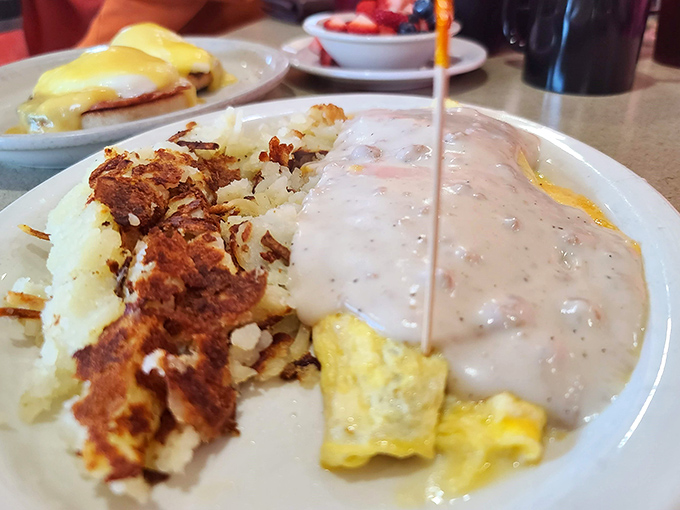 The holy trinity of breakfast comfort: golden hash browns, fluffy scrambled eggs, and creamy gravy that could make cardboard taste good.