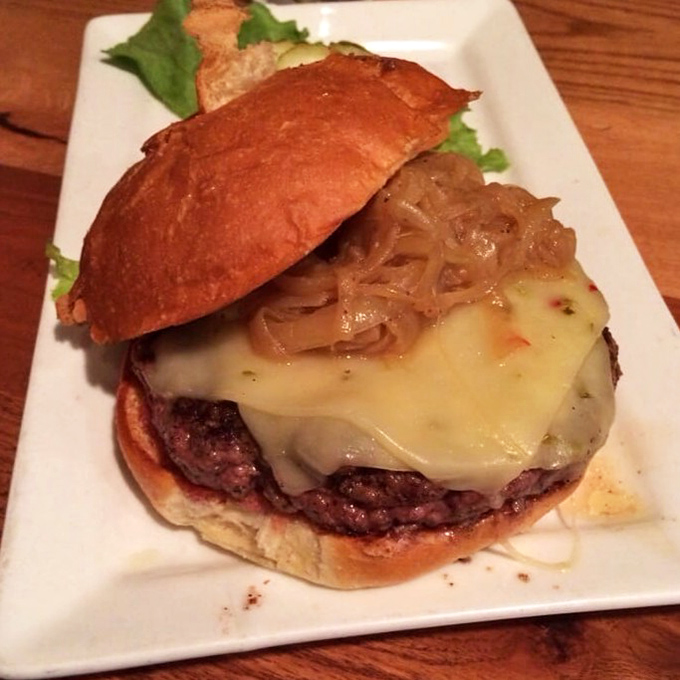 The bison burger brings something wild to the table, topped with caramelized onions and melted cheese that cascades beautifully.