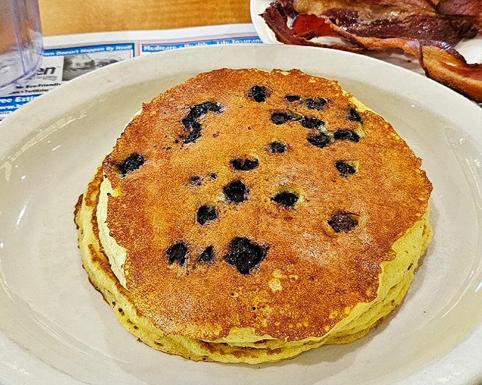 Blueberry pancakes so fluffy they practically hover above the plate, studded with berries that burst with every bite like tiny flavor bombs. 