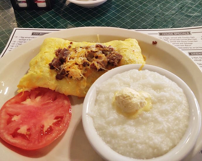 The breakfast trifecta: perfect omelet, fresh tomato, and grits that would make a Southerner weep with joy. Comfort on a plate.