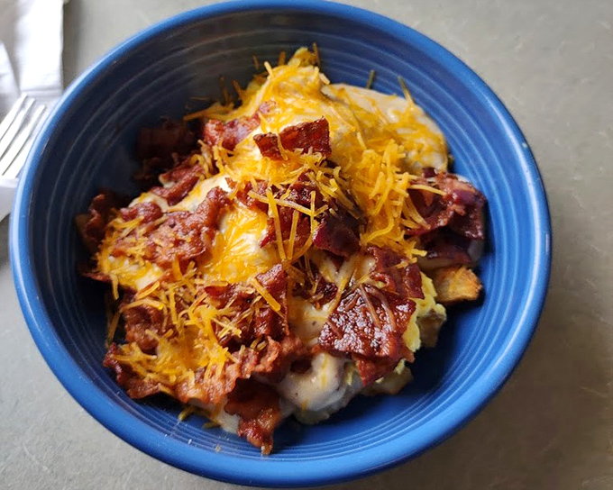 This breakfast bowl is what happens when potatoes, eggs, cheese, and corned beef decide to throw a party in a blue ceramic dish.