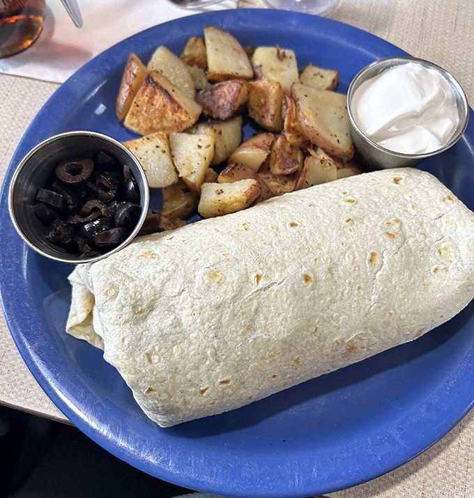 The breakfast burrito that launched a thousand return trips, flanked by home fries that deserve their own fan club.