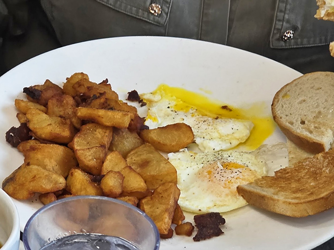 The classic breakfast trinity: eggs sunny-side up, home fries with a perfect crust, and toast ready to soak up that liquid gold yolk.