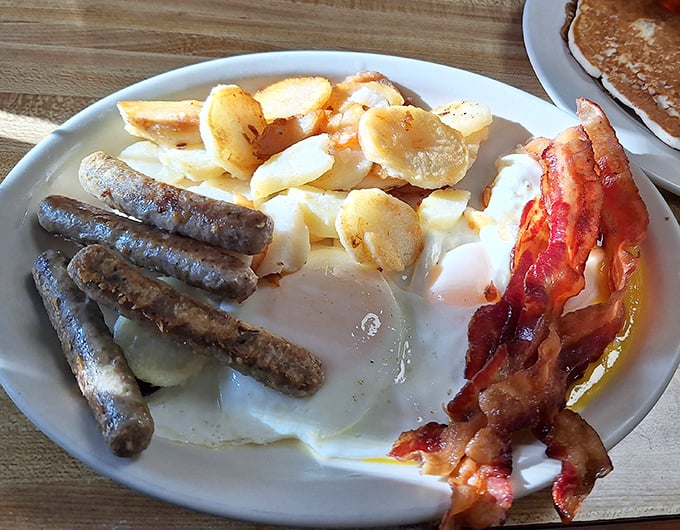 The breakfast trinity: perfectly cooked eggs, sausage links with that satisfying snap, and home fries that could convert a carb-avoider.