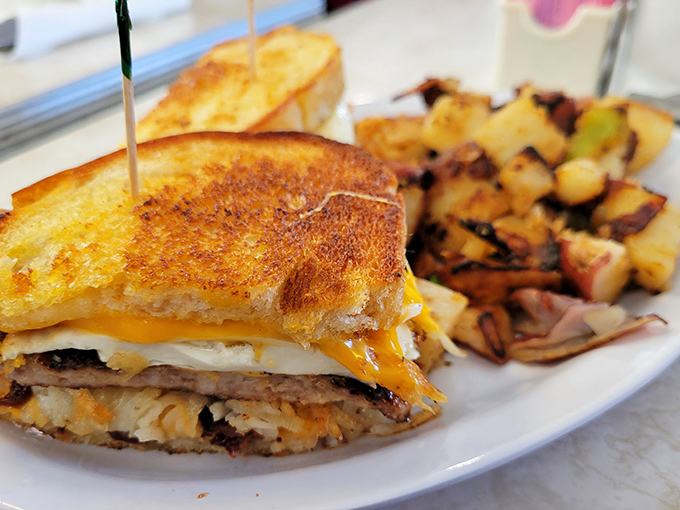 The architectural marvel known as a breakfast sandwich&mdash;perfectly grilled bread holding together a harmonious medley of morning favorites alongside crispy potatoes.