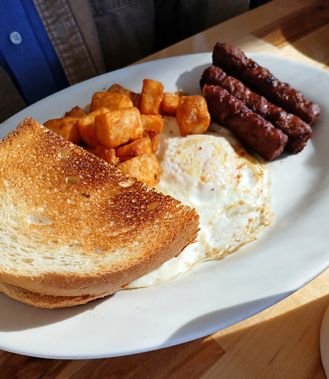 The breakfast trinity: golden toast, perfectly fried eggs, and sausage links that snap when bitten&mdash;proof that simple pleasures remain life's most reliable comforts.