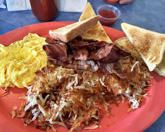 The breakfast trinity: perfectly crisp bacon, golden hash browns, and eggs with toast soldiers ready for yolk dipping duty.