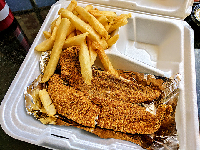 Crispy fries and golden fish fillets nestled in their takeout container like treasures. The aluminum foil adds a touch of "we care enough to keep it hot."