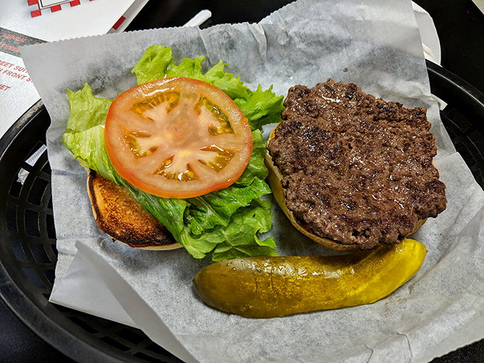 This burger sits open-faced and proud, showcasing its perfectly seasoned patty like a culinary trophy on display.