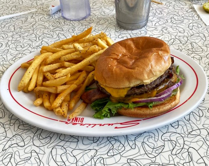 The classic American burger in its natural habitat – accompanied by crispy fries and served on a plate that's seen generations of satisfied smiles.
