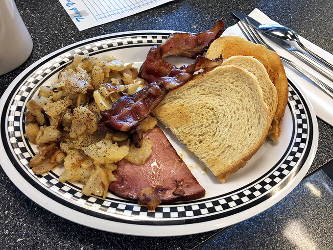 The breakfast trinity: perfectly seasoned home fries, bacon with just the right curl, and toast waiting to soak up every last bit of goodness.