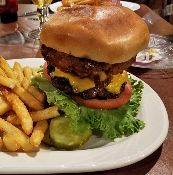A burger that requires both hands and a strategy. The pickle stands guard like it knows something special is happening.