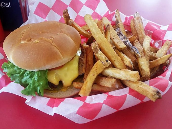 The classic combo: a perfectly proportioned cheeseburger nestled beside those legendary fries, served on red-checkered paper that signals good times ahead.