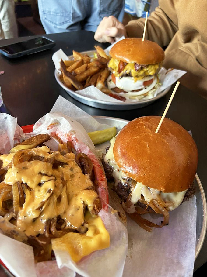 Cheeseburgers so tall they need structural engineering. The cheese cascades down like lava, while those fries huddle nearby, waiting for their moment of glory.