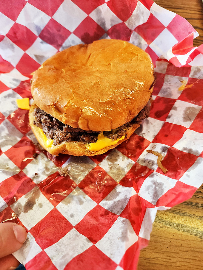 The classic cheeseburger in its natural habitat: red-and-white checkered paper, melty American cheese, and absolutely zero pretension.