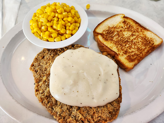 Country fried steak smothered in gravy with a side of sweet corn and Texas toast &ndash; a plate that says "you'll need a nap after this" in the most delicious way possible.