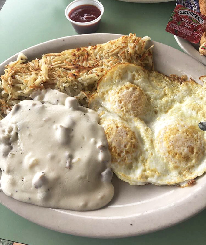 The holy trinity of diner perfection: creamy country gravy blanketing crispy chicken fried steak, sunny-side eggs, and hash browns that deserve their own fan club.