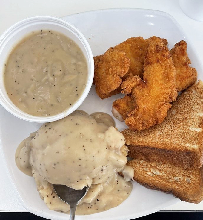 Comfort food trifecta: crispy chicken strips, creamy mashed potatoes, and gravy that could make a vegetarian question their life choices.
