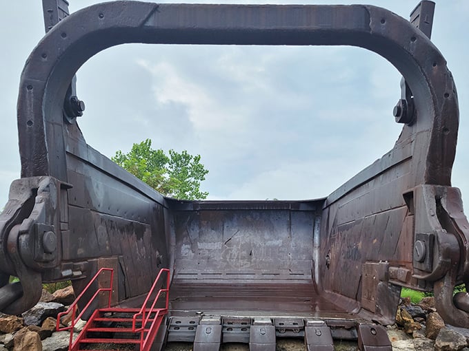 Winter reveals the bucket's stark silhouette against bare trees, a season that matches the industrial giant's raw, unadorned power.