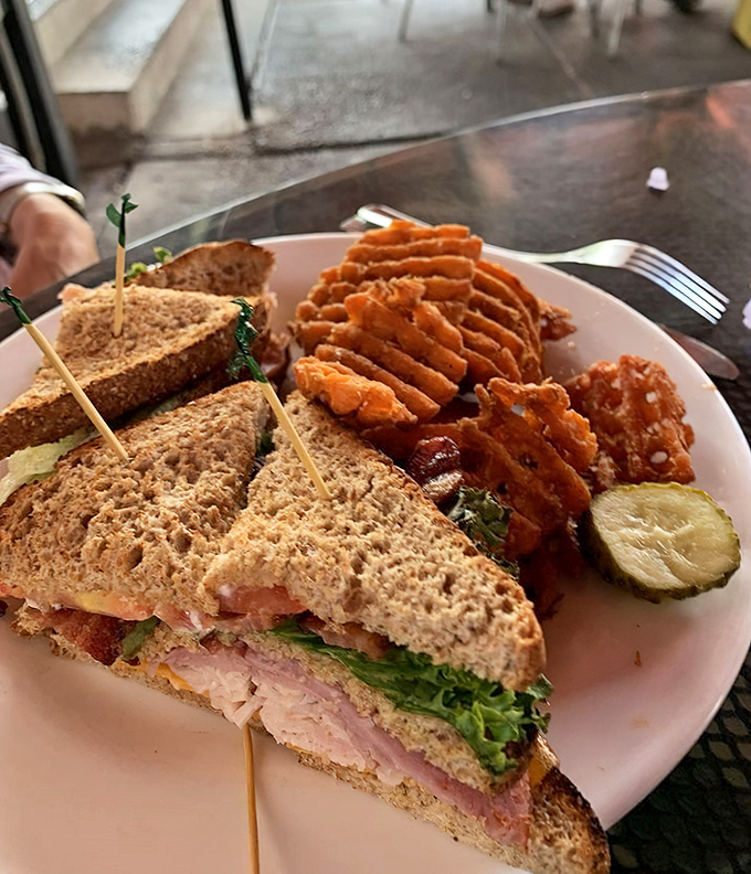 A club sandwich that stands tall and proud, flanked by sweet potato fries that deserve their own fan club.