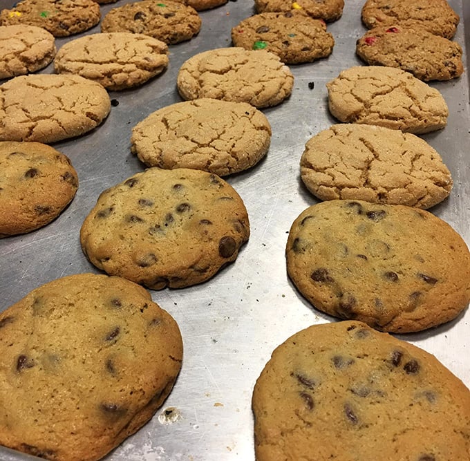 Cookies lined up like delicious soldiers ready for duty. Some with chocolate chips, others with mystery ingredients that will haunt your dreams in the best possible way.