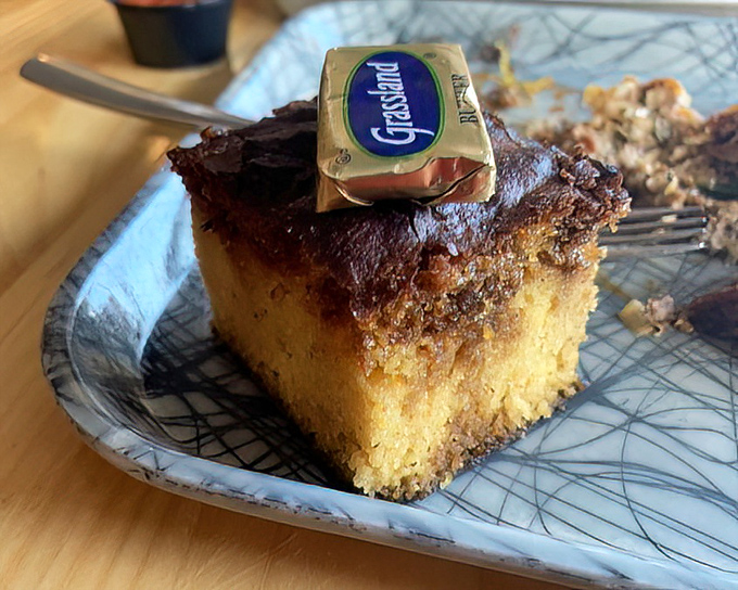Cornbread topped with a pat of butter that's melting like your resolve to "just have one bite." The tiny Grassland logo is a humble brag.
