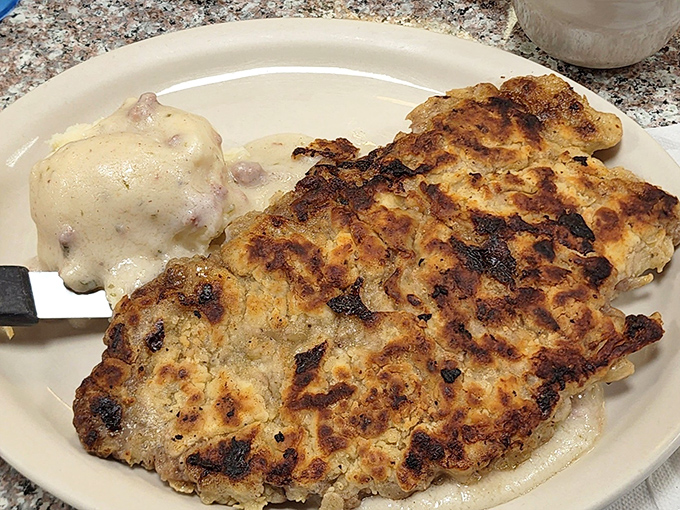 Country fried steak with a golden crust that crackles like autumn leaves, paired with gravy that could make cardboard taste gourmet.