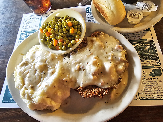 Country fried steak smothered in creamy gravy alongside mashed potatoes – the kind of plate that demands a nap afterward but is worth every yawn.