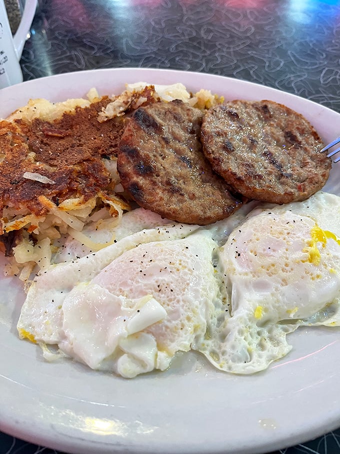 The breakfast trinity: perfectly cooked eggs, savory sausage patties, and home fries that could make a potato proud.