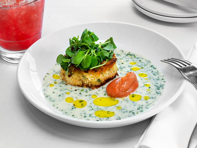 The crab cake sits like royalty in a pool of herb-flecked sauce, wearing a crown of microgreens that says, "Yes, I'm worth every penny."