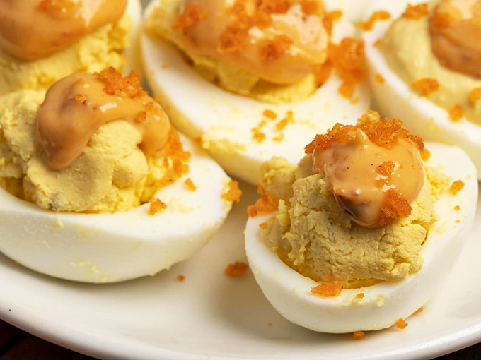 Deviled eggs elevated to heavenly status with creamy filling, a touch of sauce, and that sprinkle of seasoning that says "these aren't your grandma's eggs" (though she'd approve).