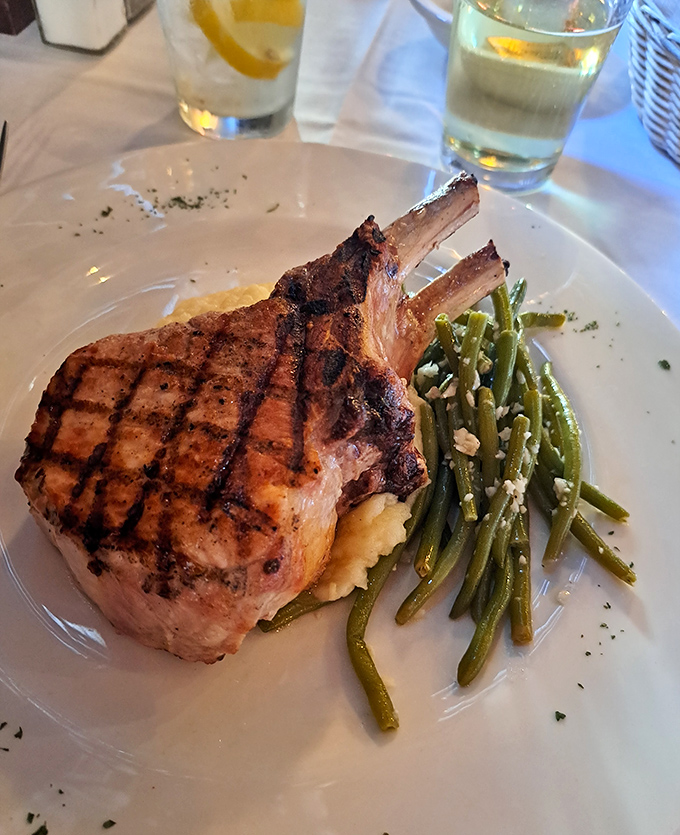 This double bone-in pork chop has more grill marks than a summer barbecue competition winner, paired with green beans that actually make vegetables exciting.