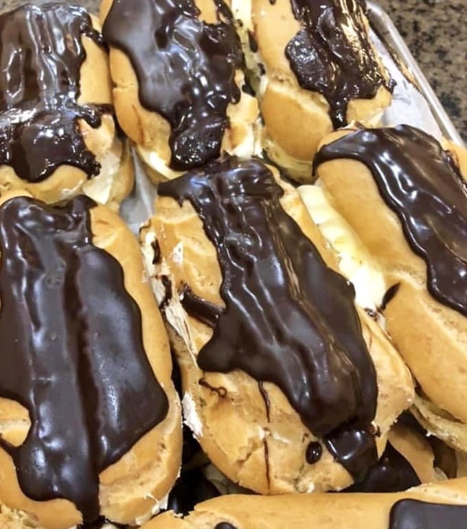 Chocolate-dipped eclairs that deserve their own Instagram account. The cream filling peeks out like it's playing hide-and-seek with your willpower.