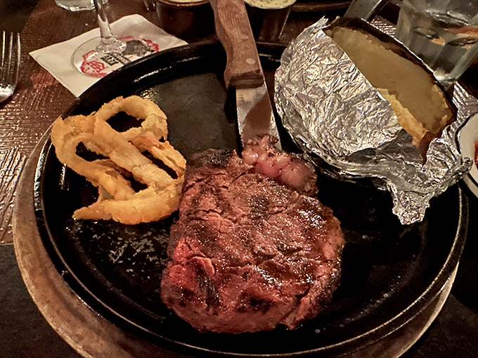 A filet mignon so perfectly seared it could make a vegetarian question their life choices, served with crispy onion rings and a baked potato.