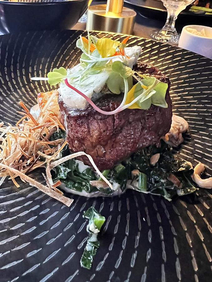 The filet mignon that launched a thousand food pilgrimages, perched atop greens like a meaty monument to perfection. Worth every mile of the journey.