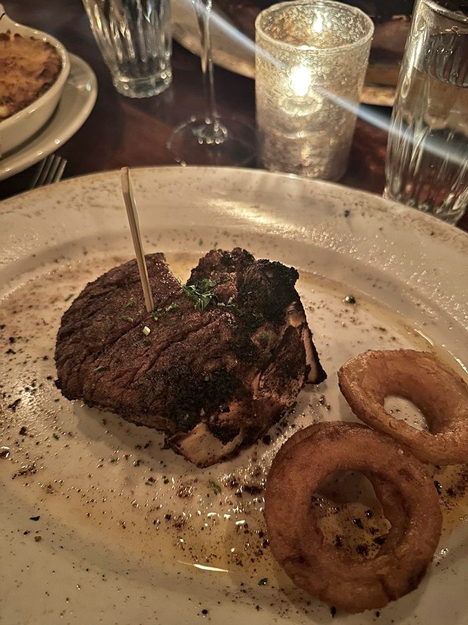 A perfectly cooked filet mignon with textbook char marks, accompanied by onion rings that look like they've earned their Ph.D. in crispiness.