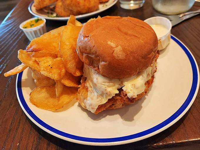 The sandwich that launches a thousand return trips: crispy, golden seafood nestled in a soft bun with house-made chips standing guard.