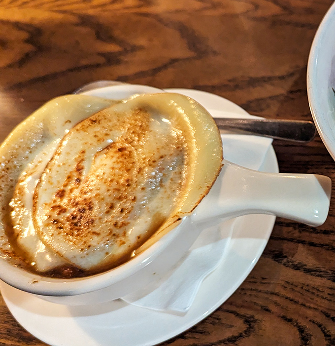 French onion soup wearing its cheese cap like a beret, because even soup deserves to feel fancy sometimes.