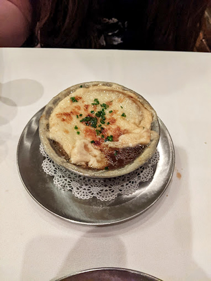 The legendary French onion soup arrives like a work of art—a bubbling cauldron of savory broth beneath a golden cheese canopy.