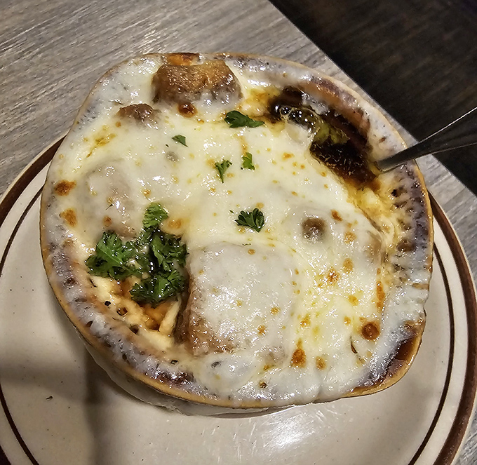 French onion soup that's more blanket than broth &ndash; a cheese canopy so glorious it deserves its own architectural award.