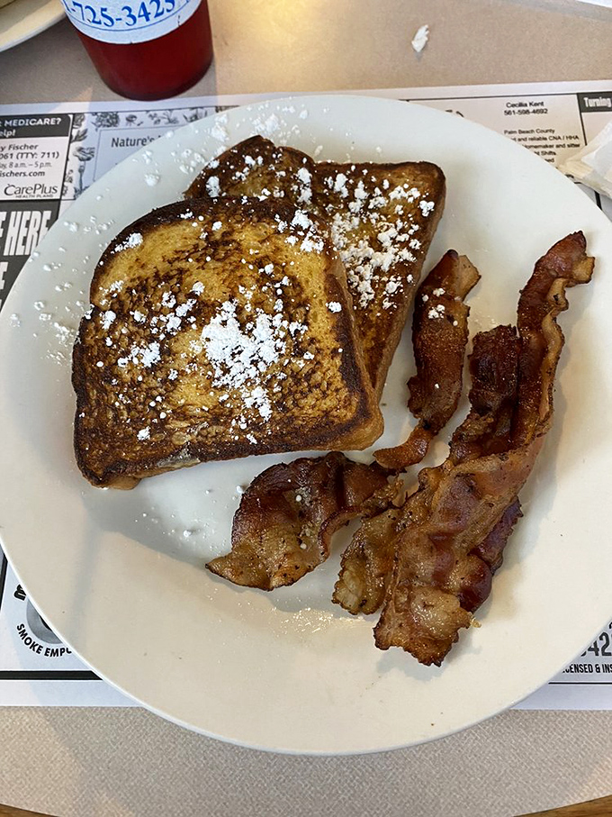 French toast dusted with powdered sugar alongside crispy bacon &ndash; proof that the sweet-savory combination is humanity's greatest culinary achievement.