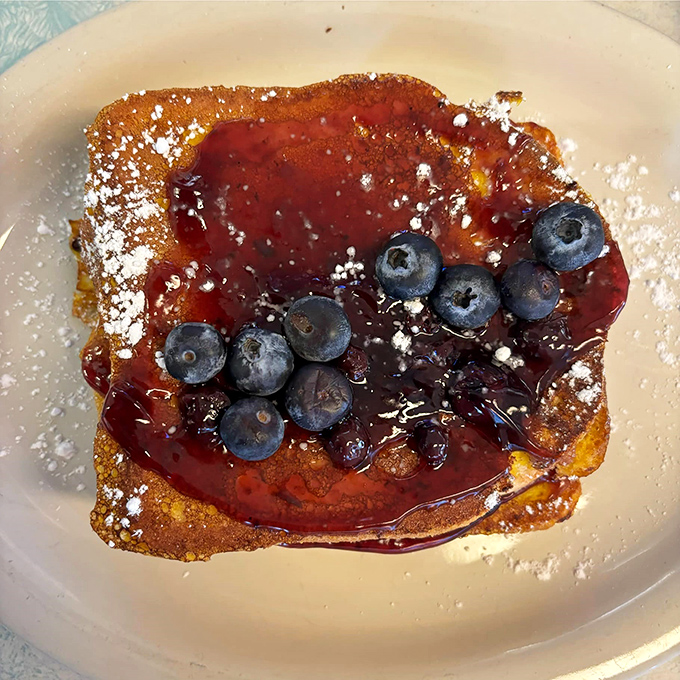 French toast that dreams are made of &ndash; golden, crispy edges giving way to custardy centers, crowned with fresh blueberries and a dusting of powdered sugar.