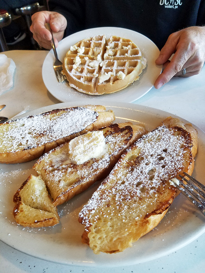 French toast and waffles sharing a plate like old friends. Dusted with powdered sugar and waiting for maple syrup's sweet embrace.