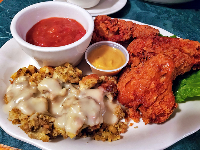 Crispy fried chicken alongside creamy gravy-smothered stuffing – proof that sometimes the simplest pleasures are the most profound.