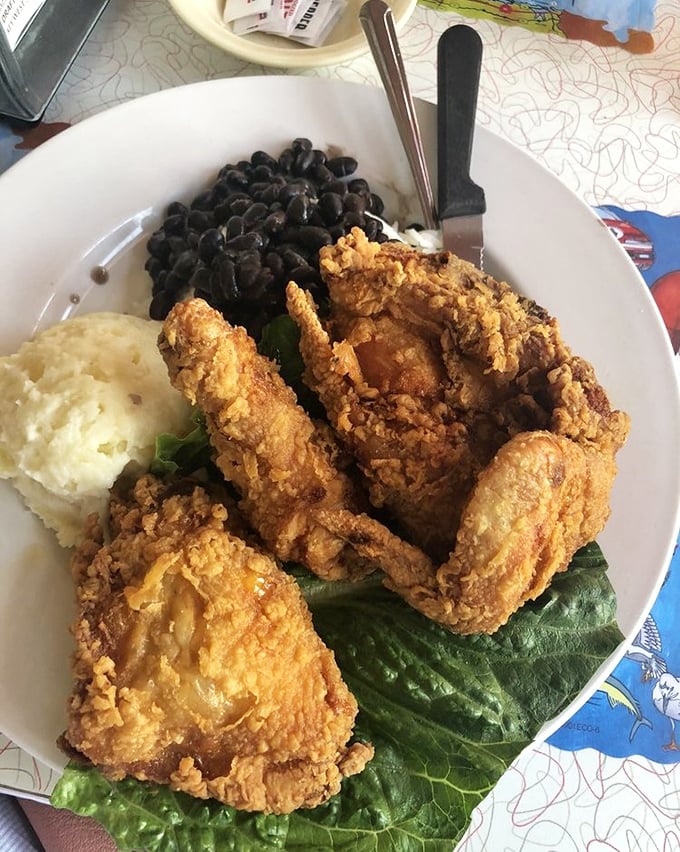 Golden-brown fried chicken with a perfectly seasoned crust sits alongside creamy mashed potatoes and black beans&mdash;comfort food that transcends regional boundaries.