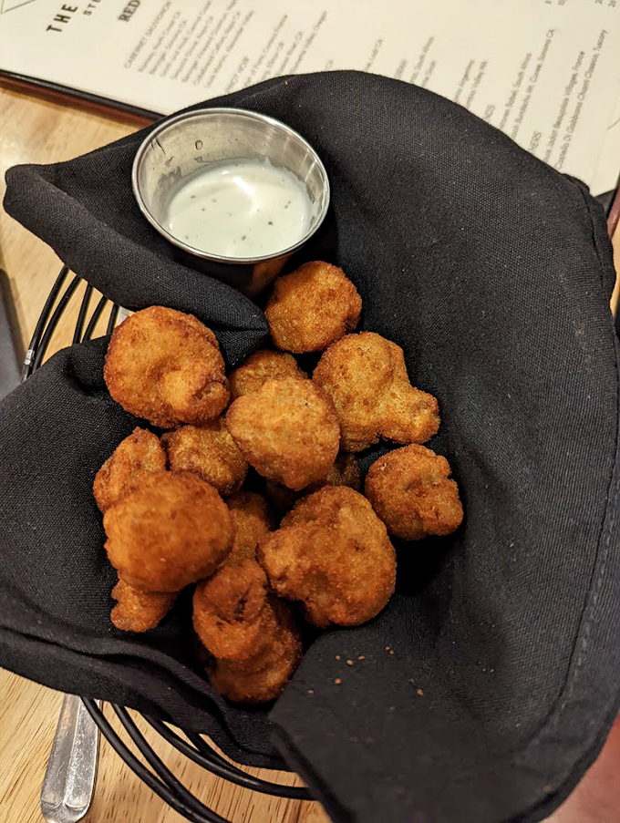 These golden-fried mushrooms nestled in a black napkin aren't just appetizers&mdash;they're little umami bombs waiting to detonate on your taste buds. 